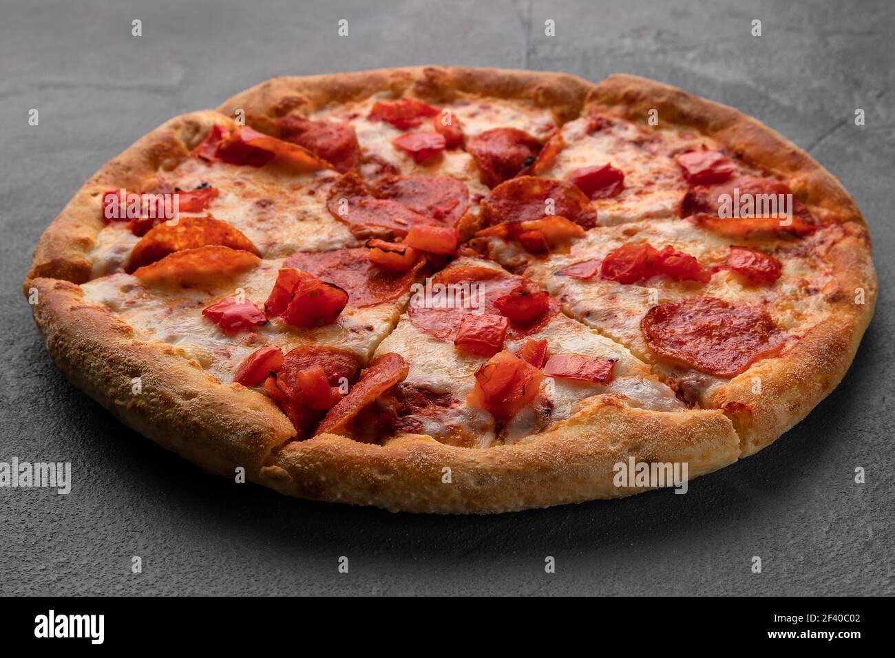 whole fresh round pizza with pepperoni and mozzarella cheese on a gray ...