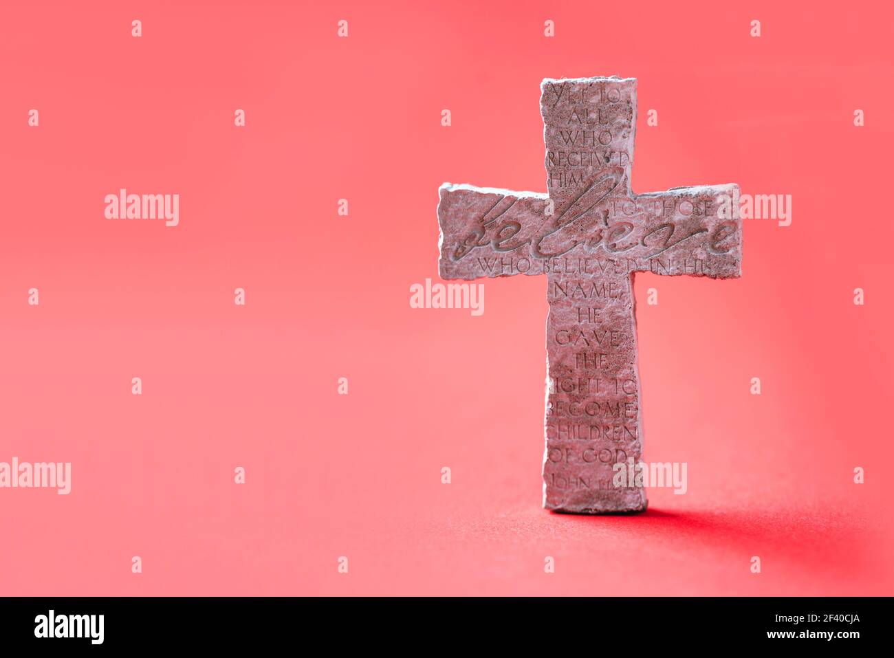 Stone cross with inscription Believe on red background, Copy space ...