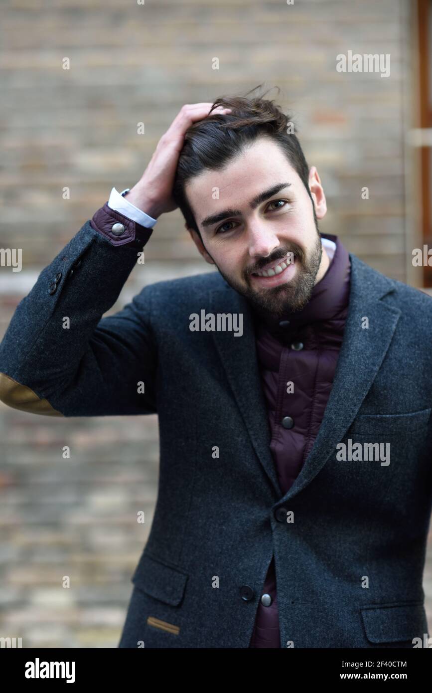 Young bearded smiling man, model of fashion, in urban background ...