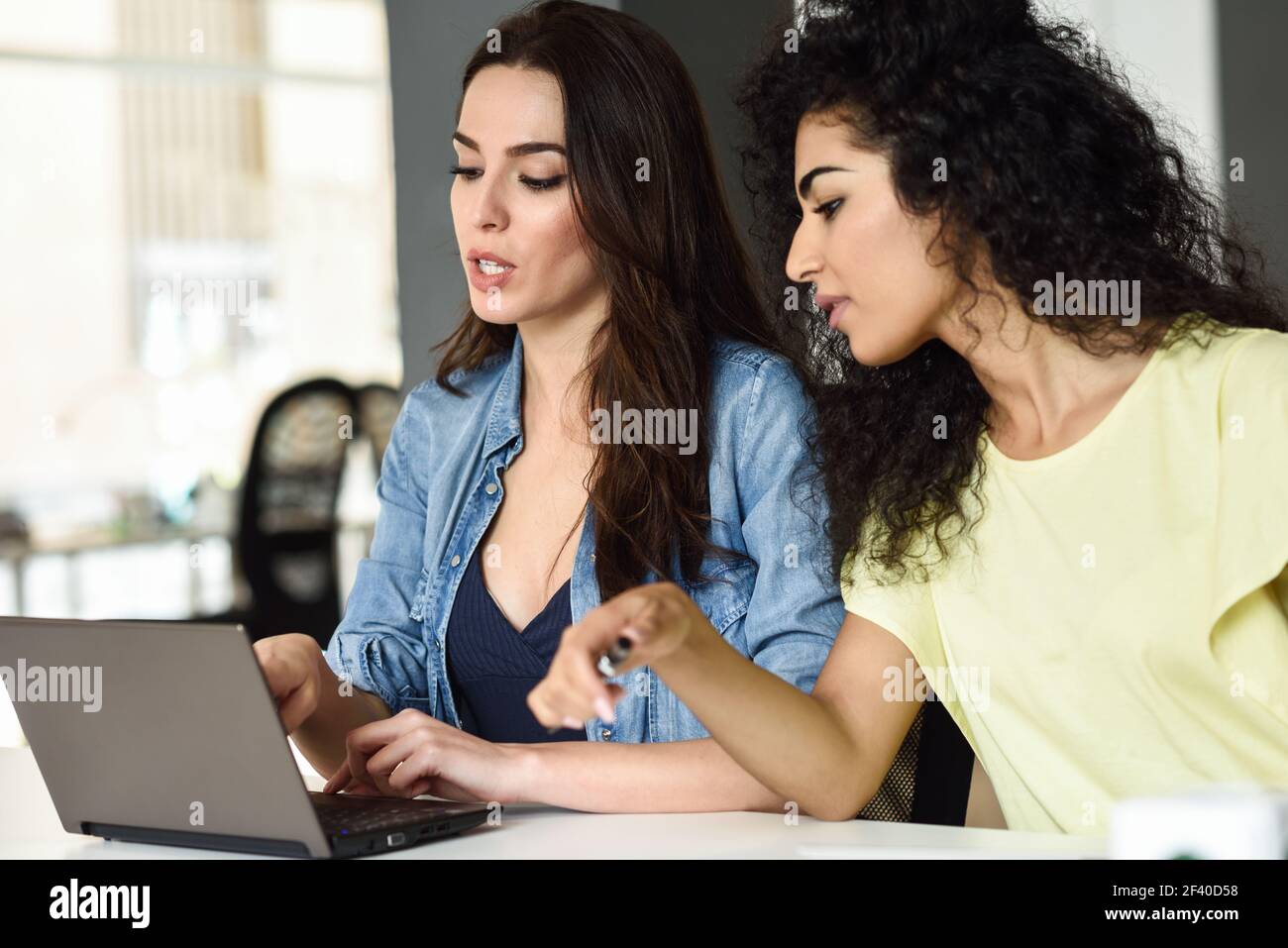 Two young women studying with a laptop computer on white desk ...