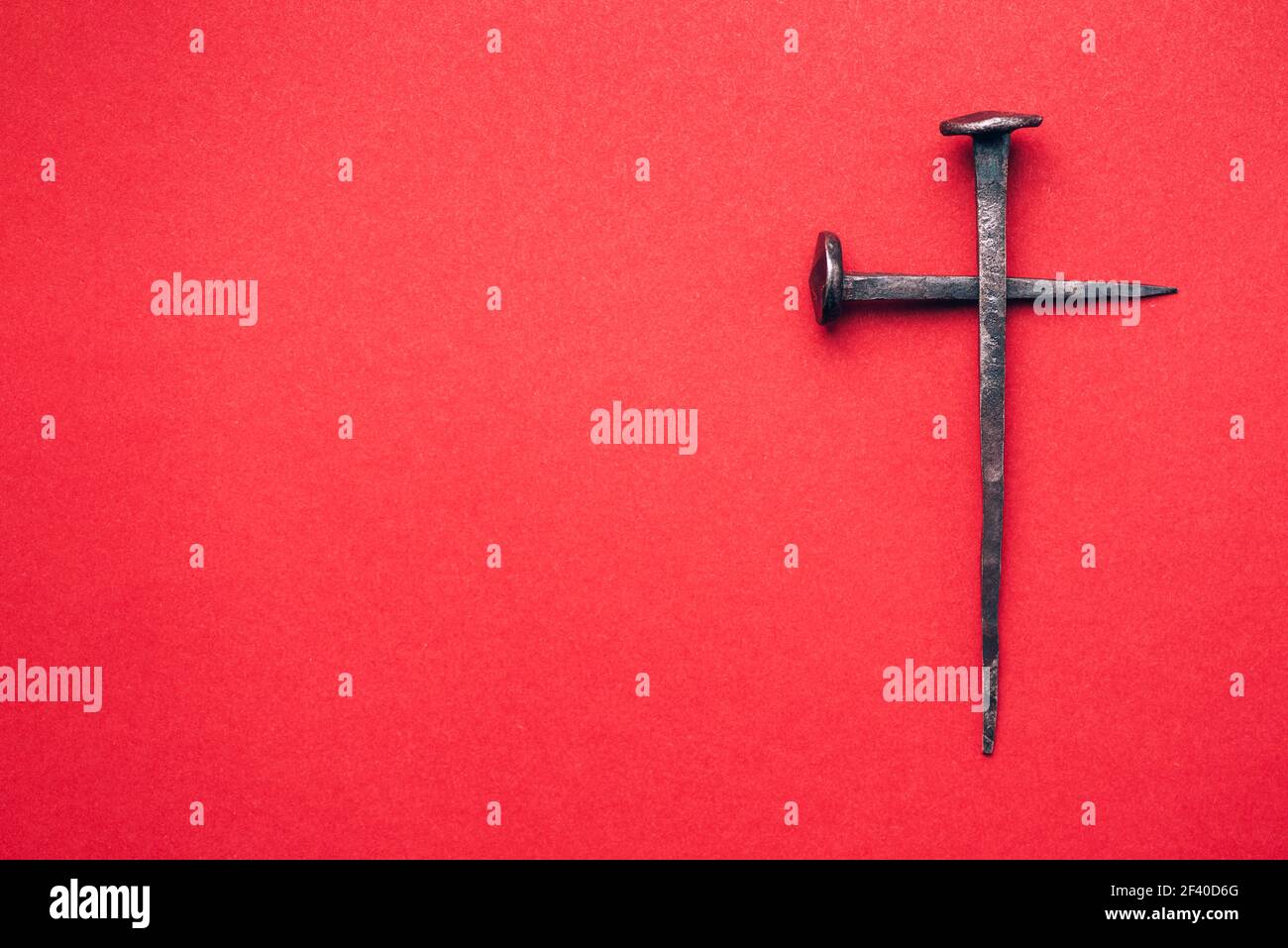 Cross made with rusty nails and drops of blood on red background. Copy ...