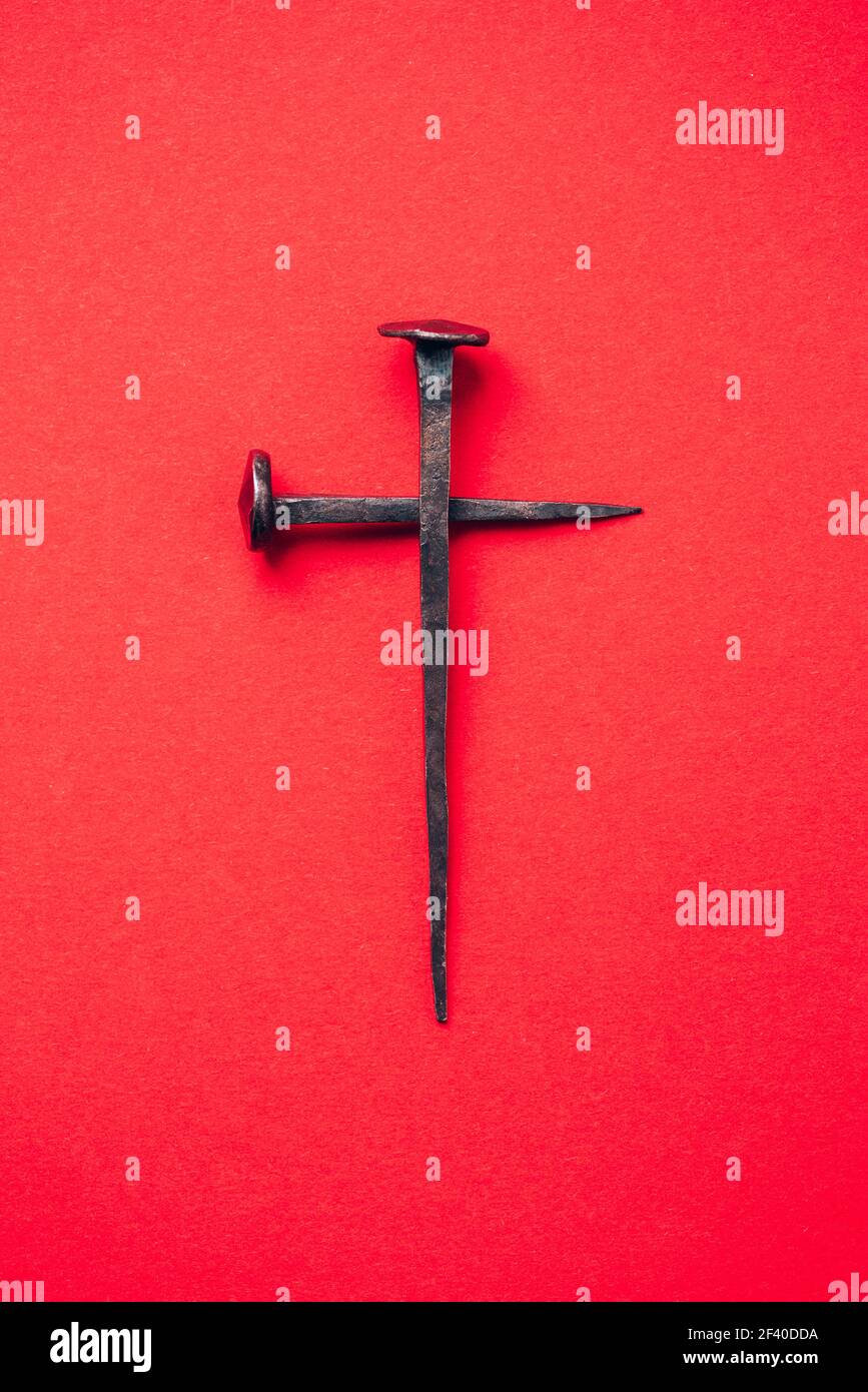 Cross made with rusty nails and drops of blood on red background. Copy ...