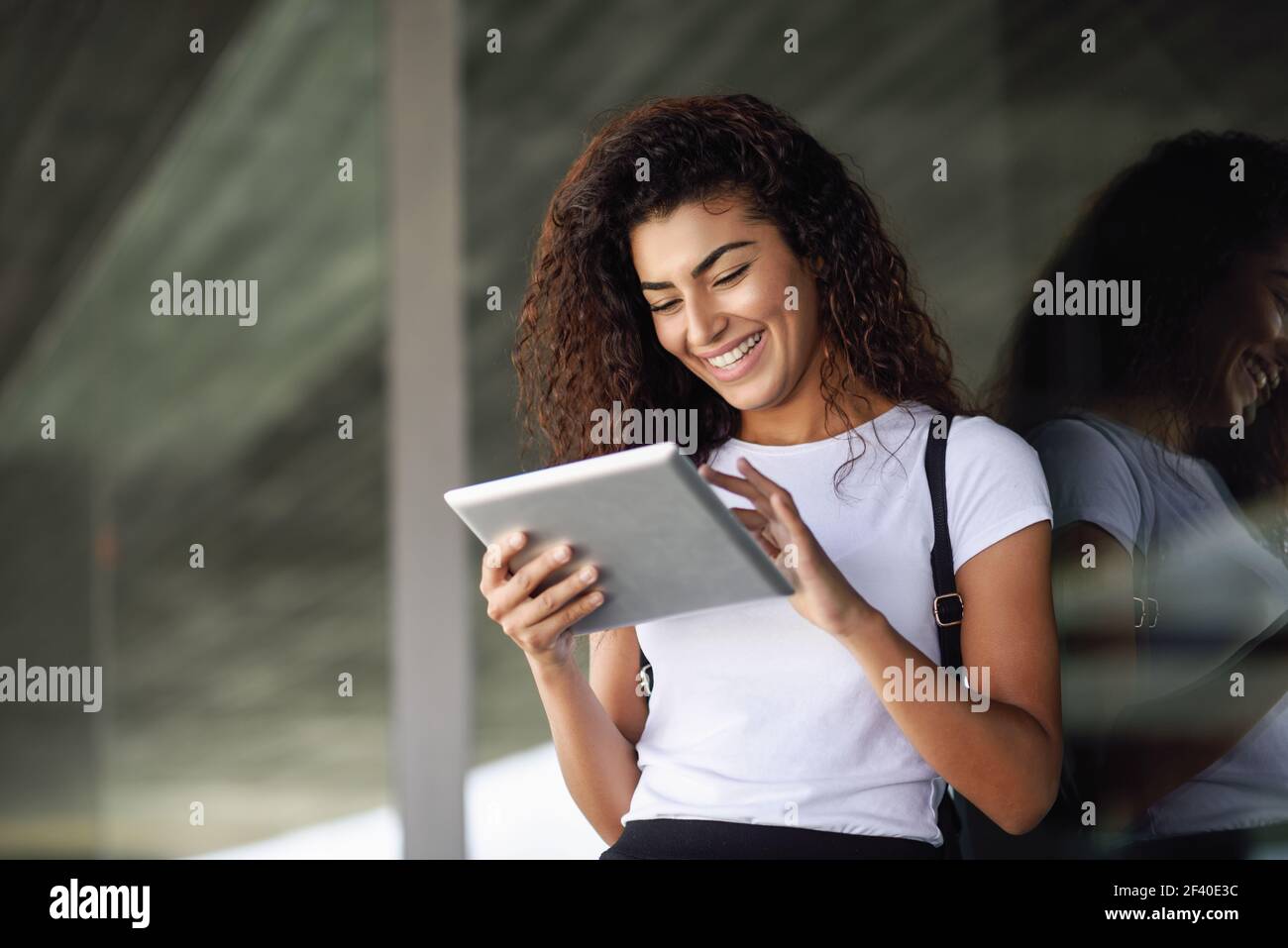 Happy young Arab woman using digital tablet in business background ...