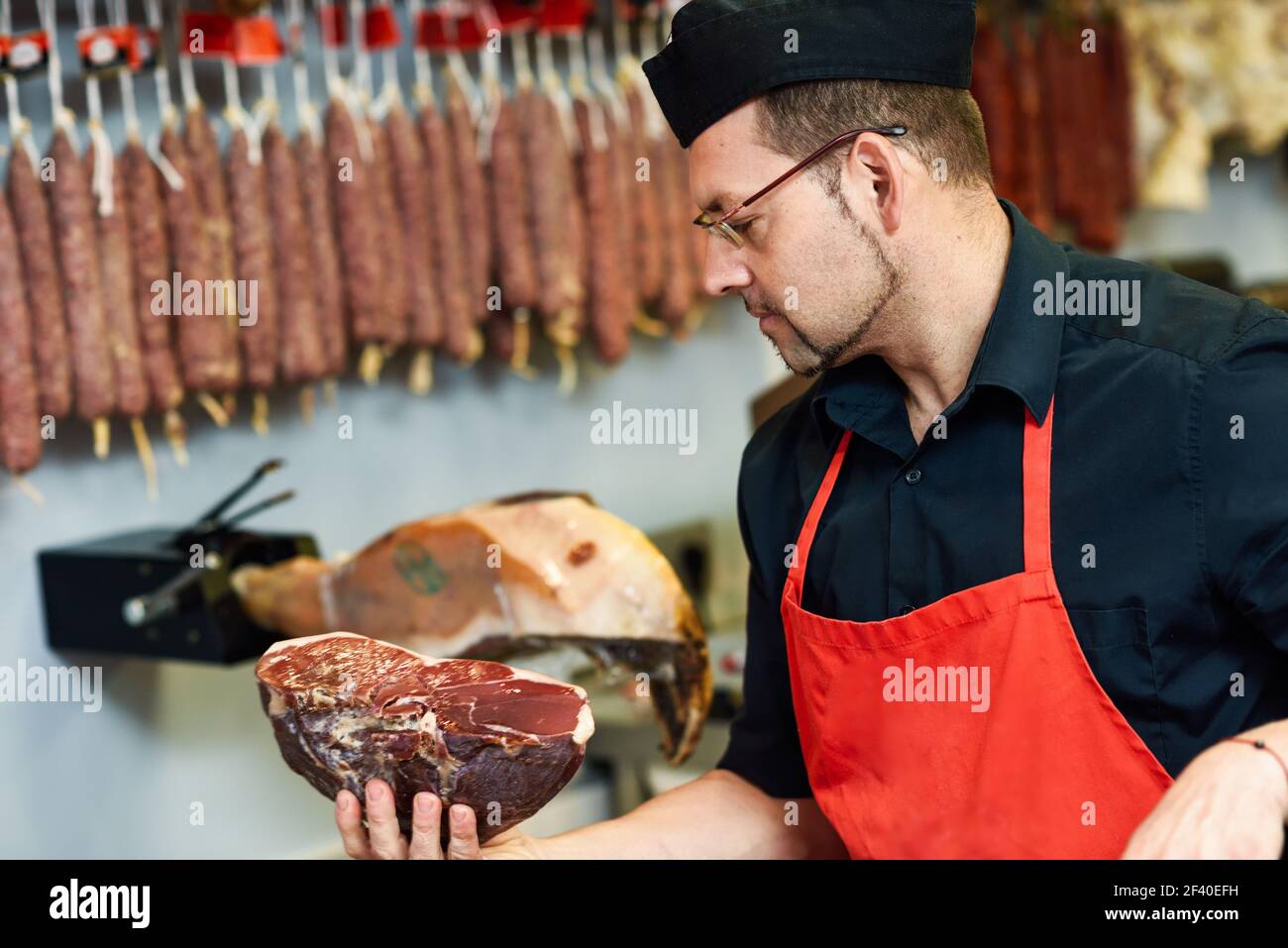 Butcher with a piece of ham in his hand inside a butcher shop Stock ...