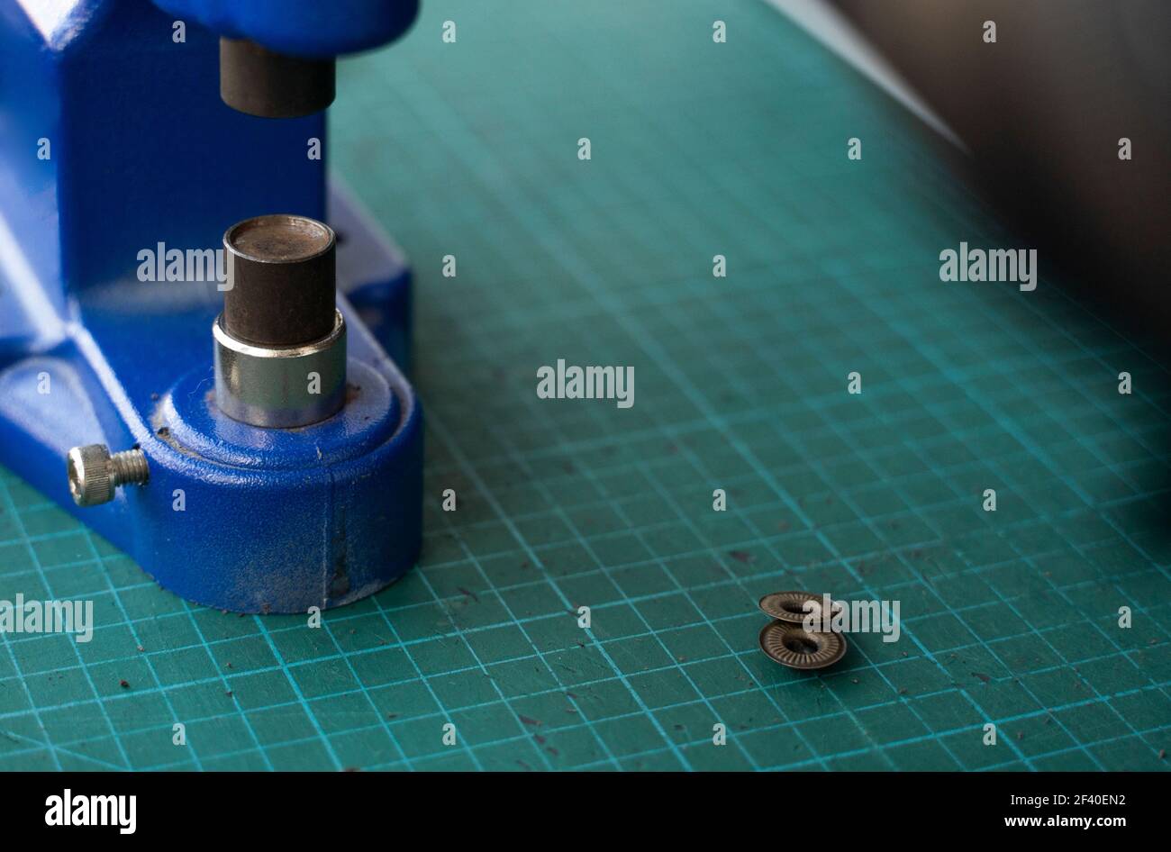 Artisan using hand press for setting snaps in leather for makes a ...
