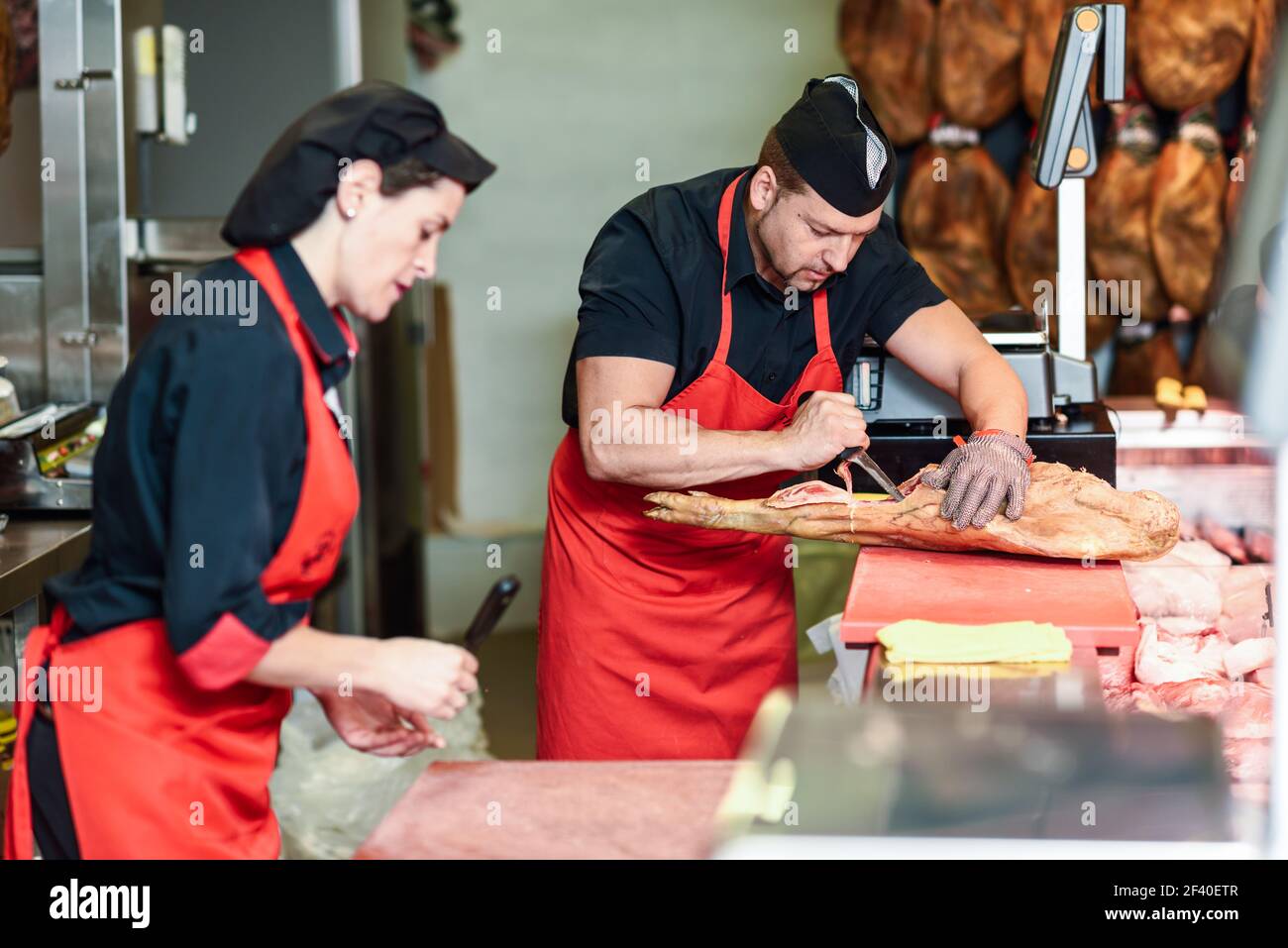 Male and female butchers boning a ham in a modern butcher shop Stock ...
