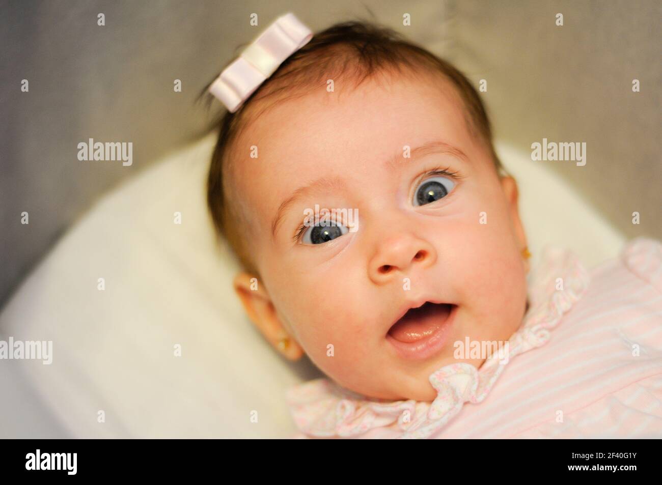 Little baby girl with funny surprise expression on her face. Two months ...