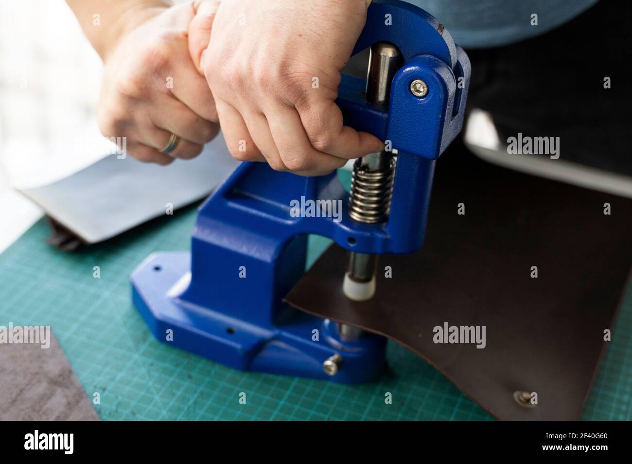 Artisan using hand press for setting snaps in leather for makes a ...