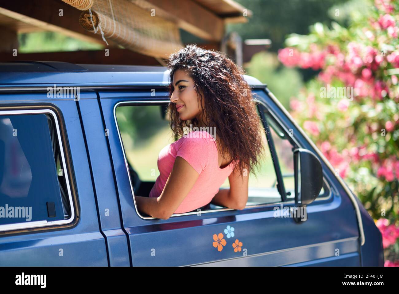 Happy young woman in a camper van enjoying spring time in a beautiful ...