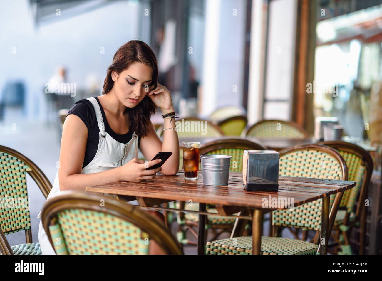 Beautiful woman with blue eyes sitting on urban cafe texting with smart ...