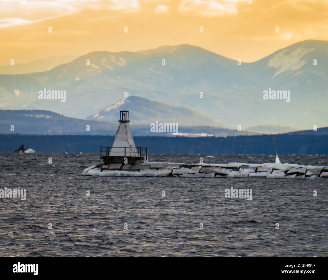 sun setting on Lake Champlain breakwater's lighthouse with the ...
