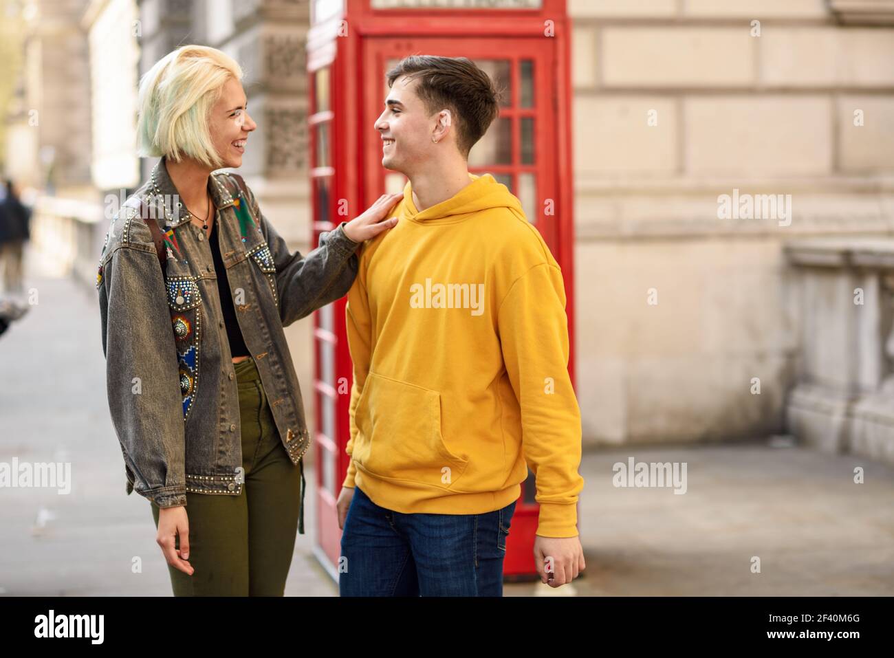 Young happy couple of friends near a classic British red phone booth ...