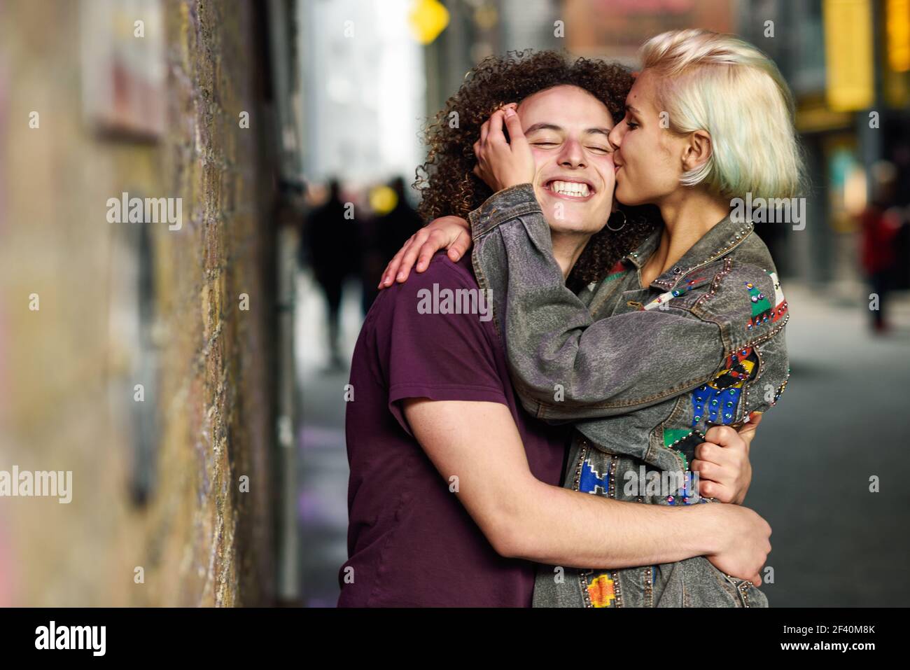 Young woman kissing her boyfriend in urban background on a typical ...