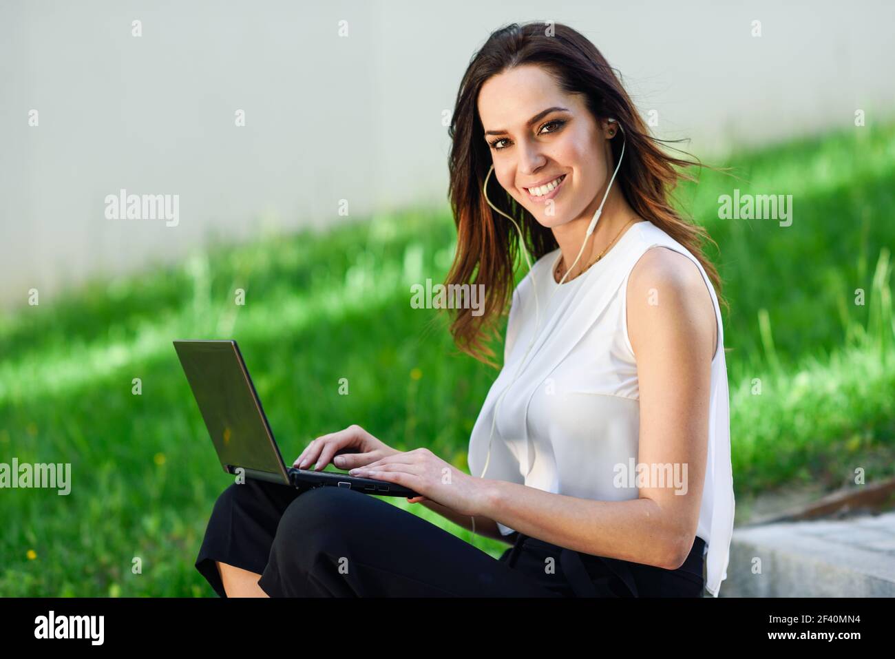 businesswoman working with her laptop computer sitting on urban steps ...