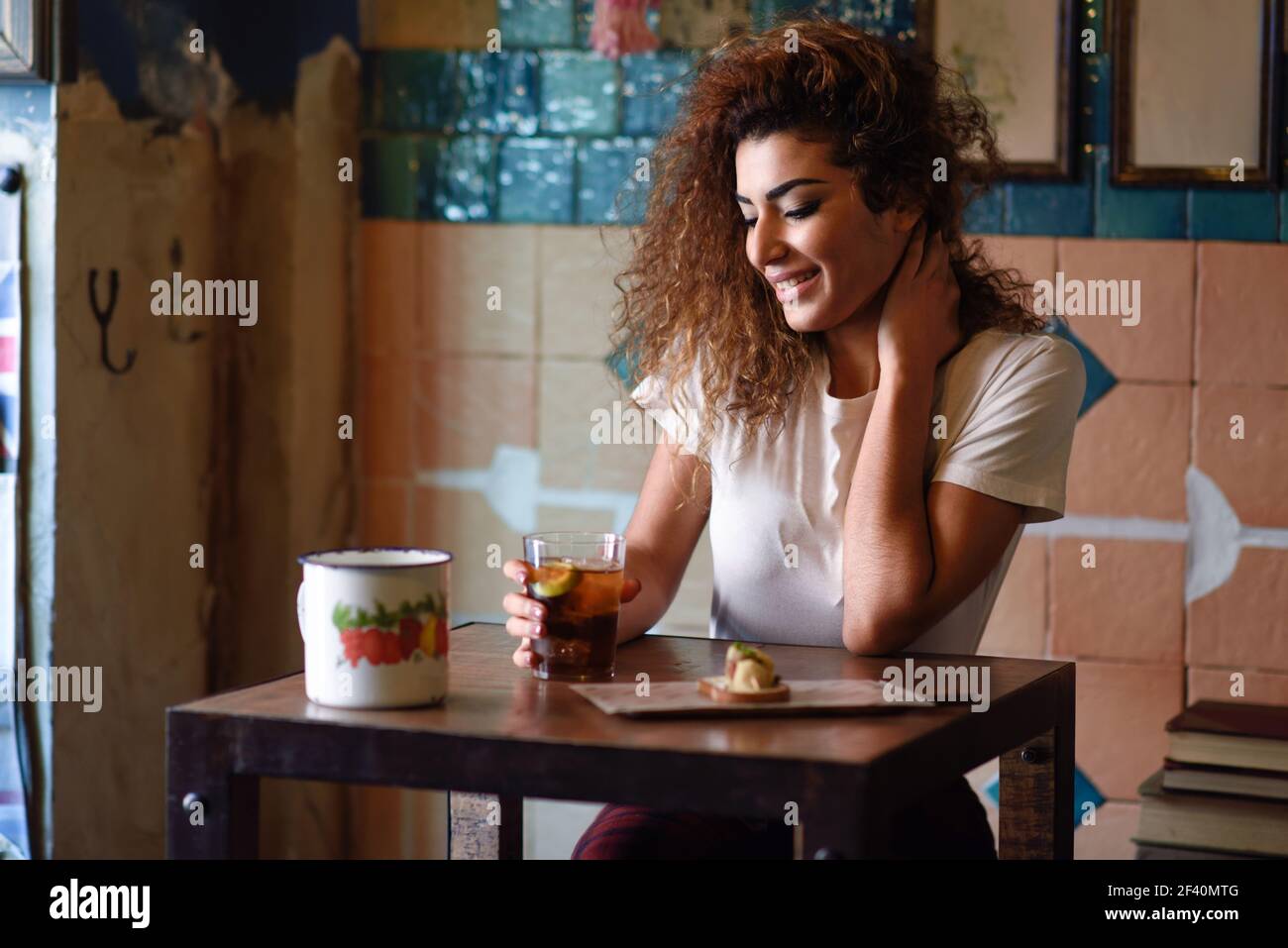 Young arabic smiling woman with black curly hairstyle sitting in a ...