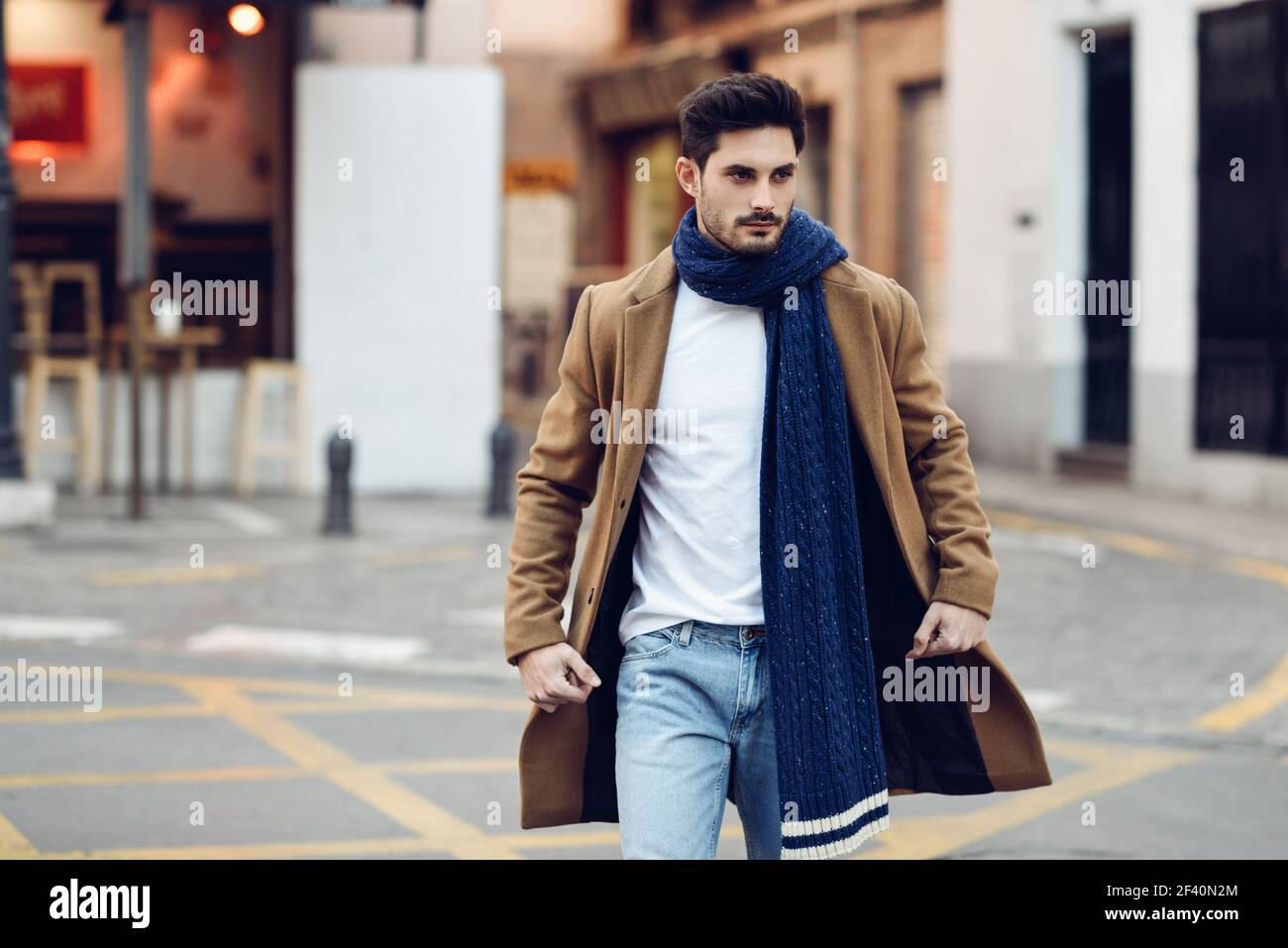 Young man wearing winter clothes in the street. Young bearded guy with ...