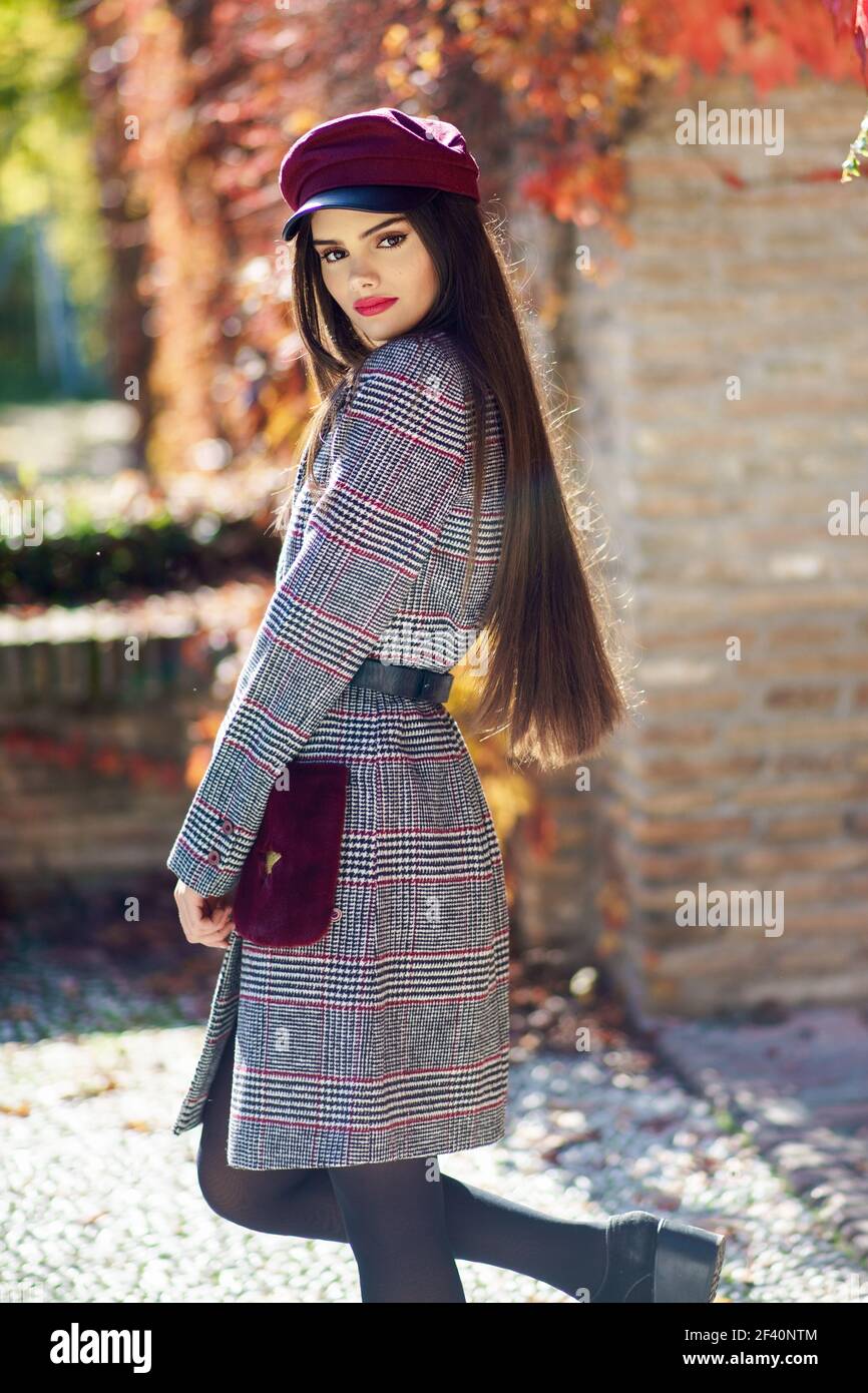 Young beautiful girl with very long hair wearing winter coat and cap in ...