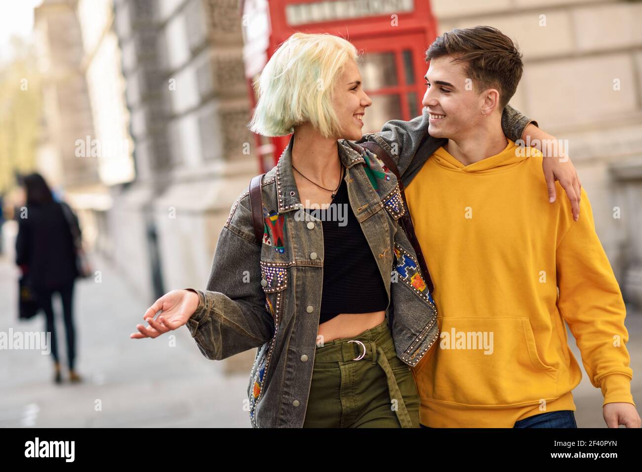 Young happy couple of friends near a classic British red phone booth ...