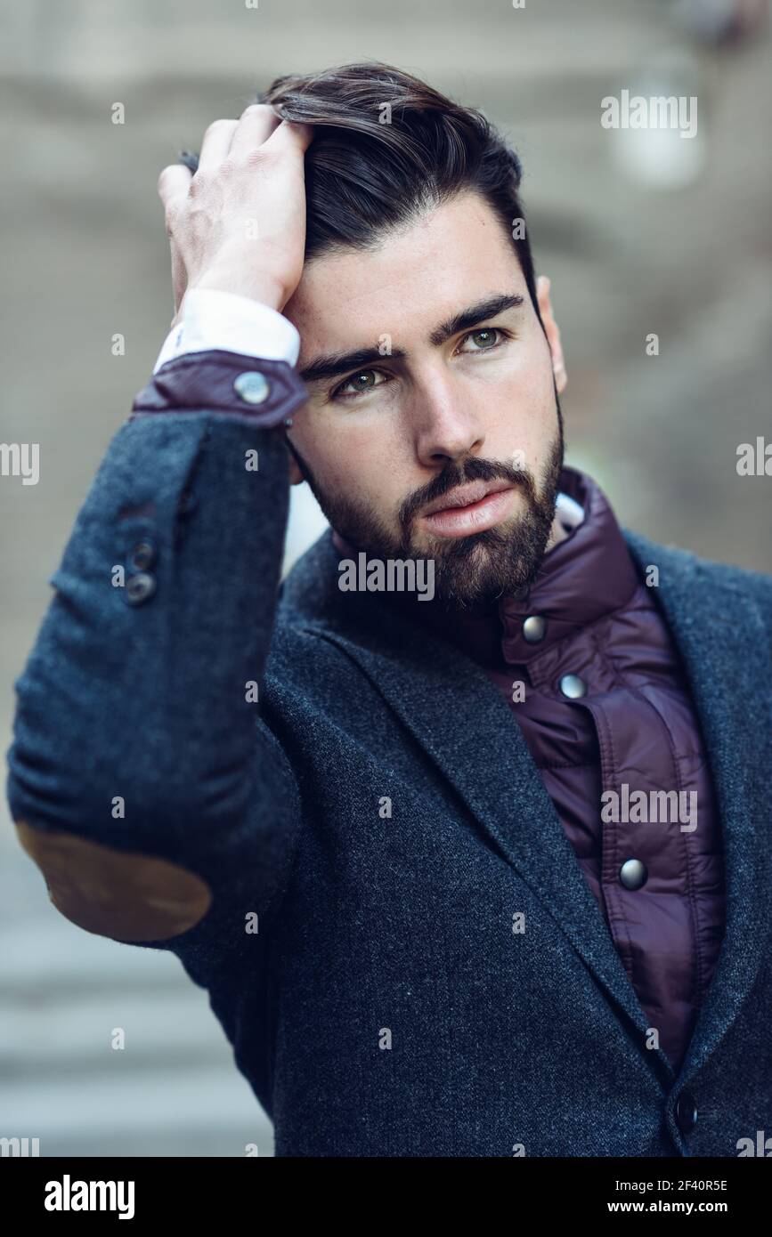 Young bearded man, model of fashion, standing in urban background ...