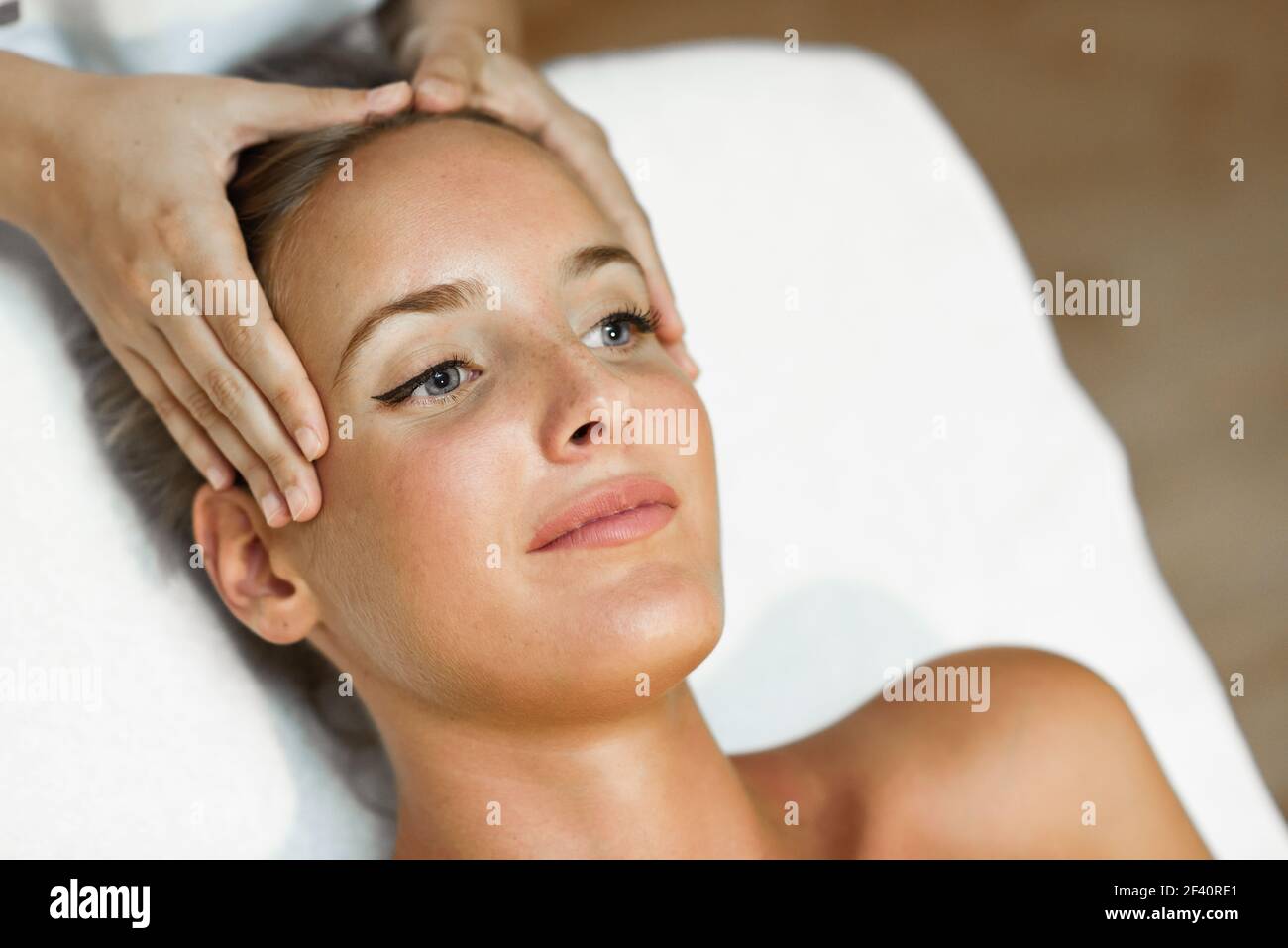 Young Blond Woman Receiving A Head Massage In A Spa Center With Blue