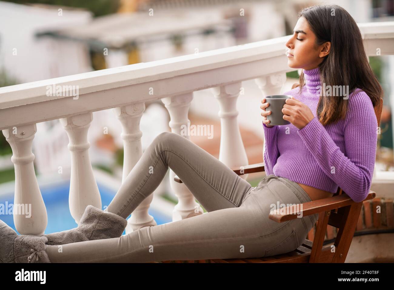 Persian woman sitting in an armchair on her balcony having a mug of ...