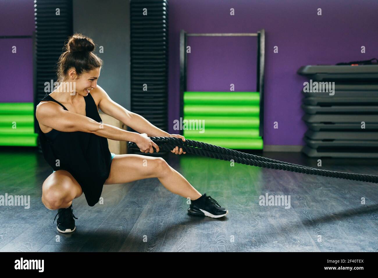 Young and athletic woman using training ropes in a gym. Fitness concept ...