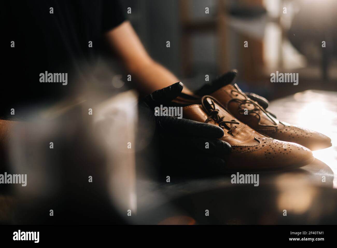 Close-up side view of hands of shoemaker shoemaker in black gloves ...