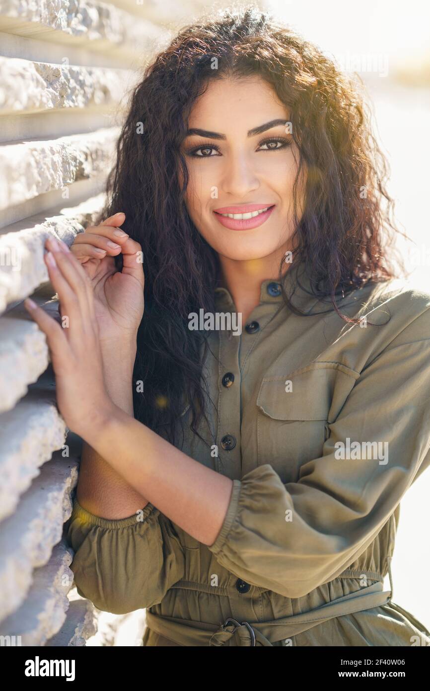 Smiling Arab Woman with curly hair in urban background. Young Arab ...