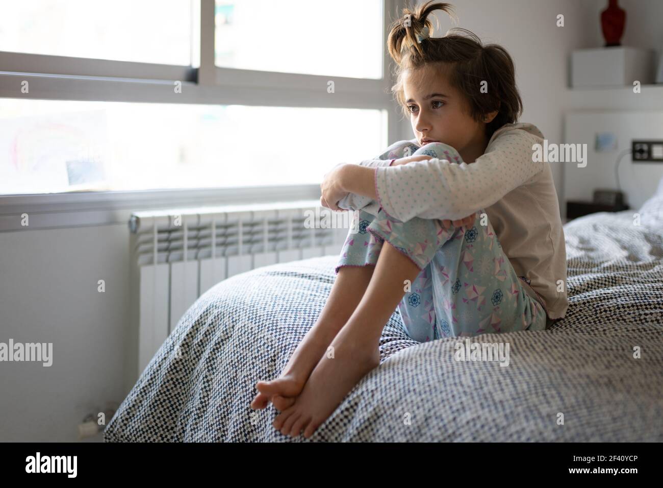 Nine-year-old girl sitting in bed at home bored by confinement. Nine ...
