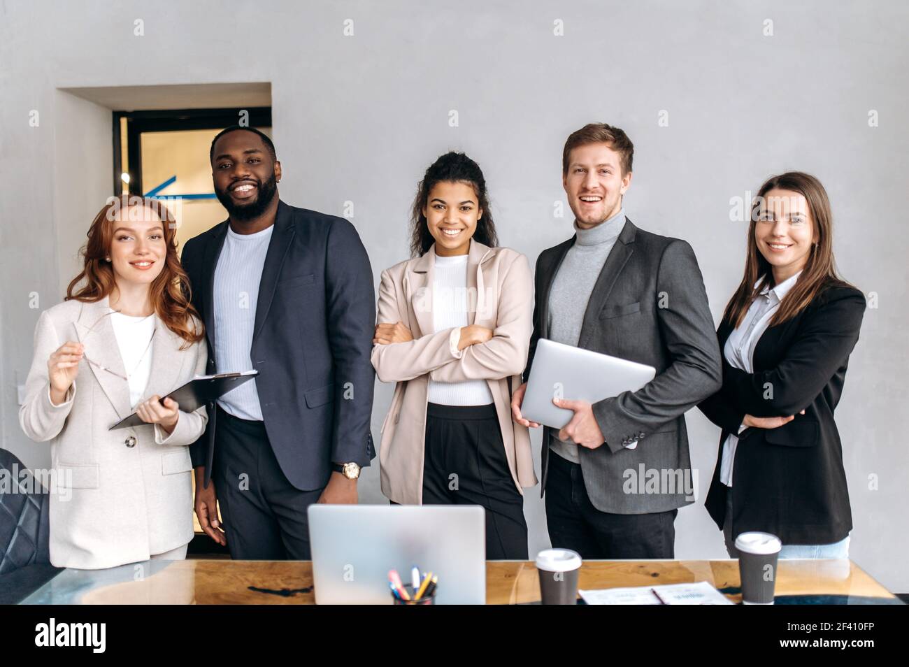 Confident stylish coworkers in formal suits are looking directly at the ...