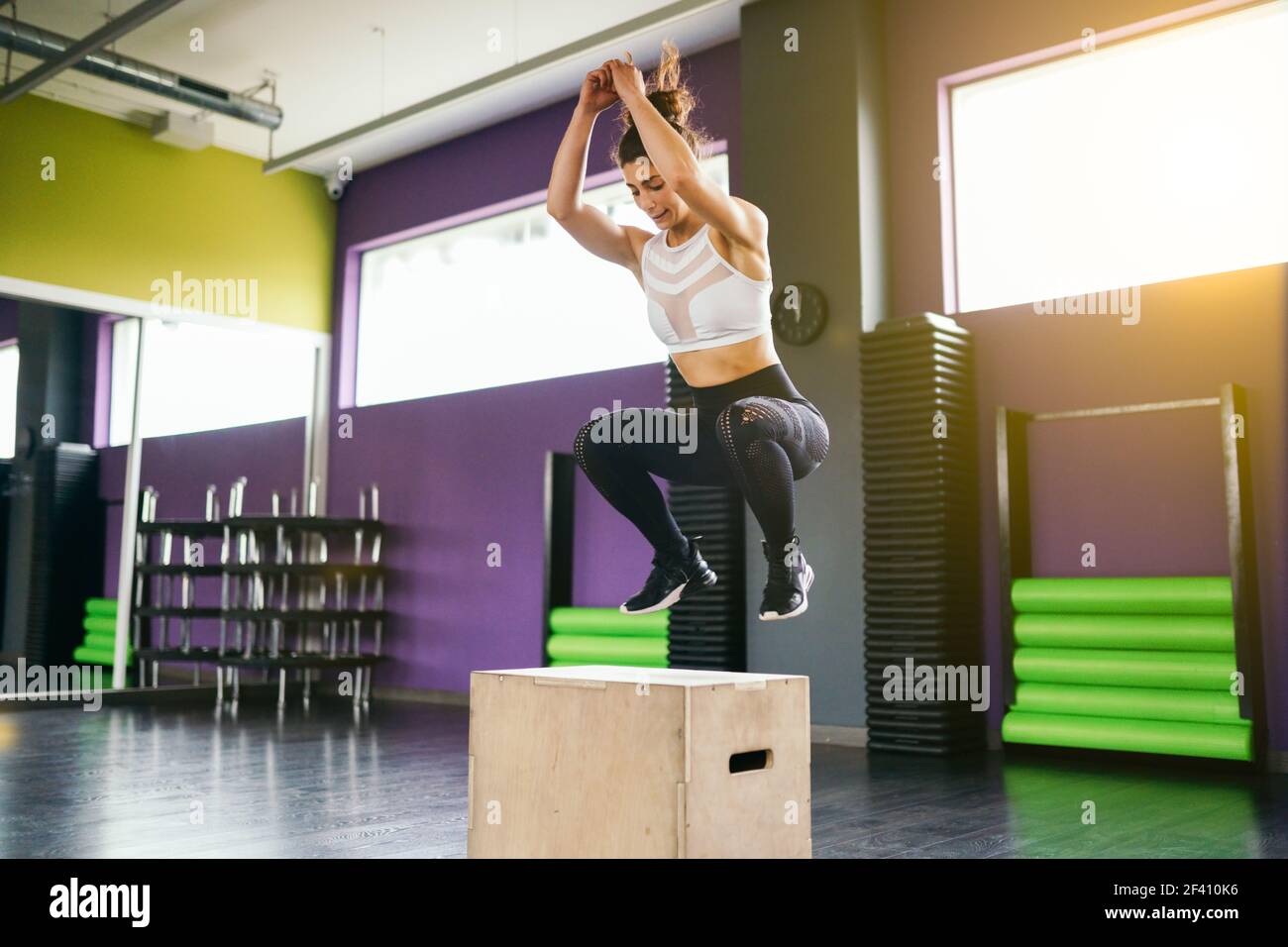Fitness woman jumping onto a box as part of exercise routine. Caucasian ...