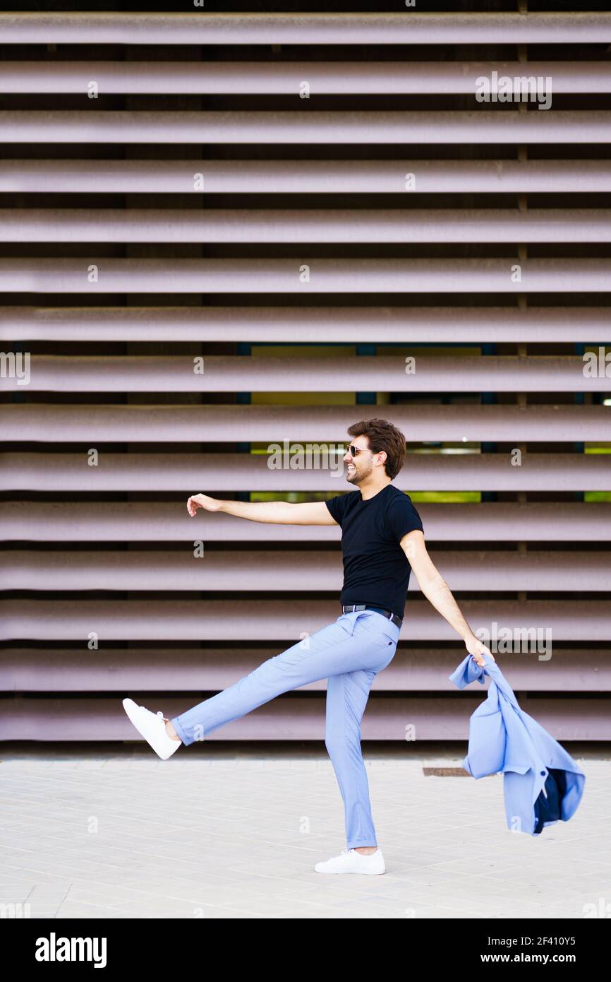 Happy young man walking funny in urban background. Happy man walking ...