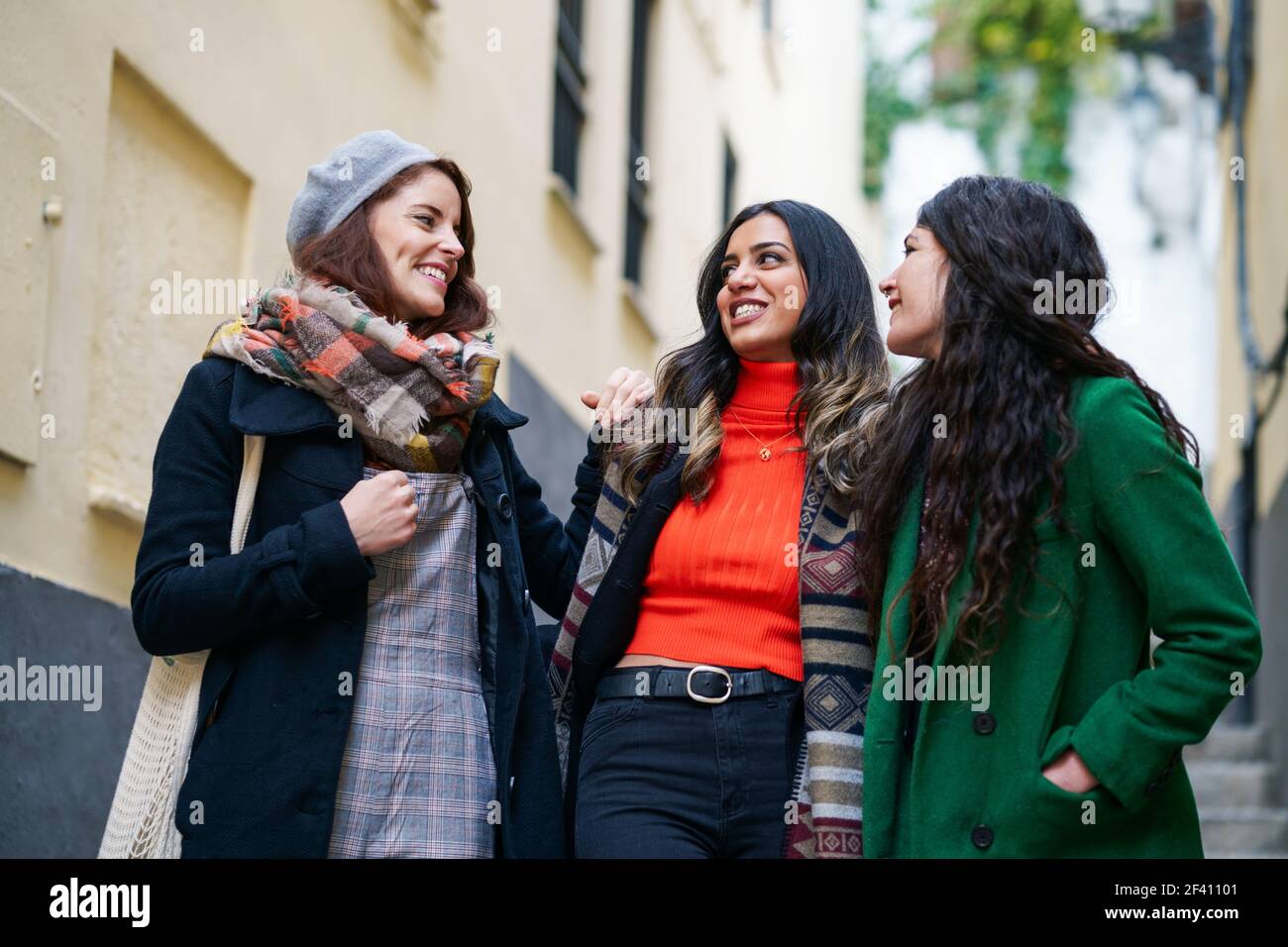 Multiethnic group of three happy woman walking in urban background ...
