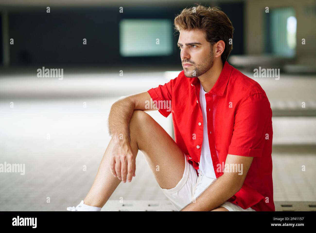 Male student sitting on a college campus bench. Young man in urban ...