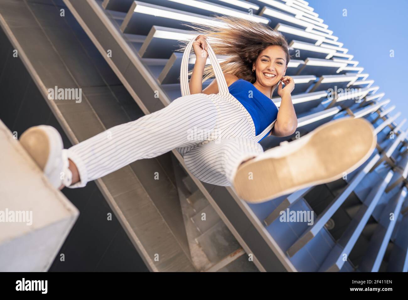 View from below of young girl throwing her foot in the air in urban ...