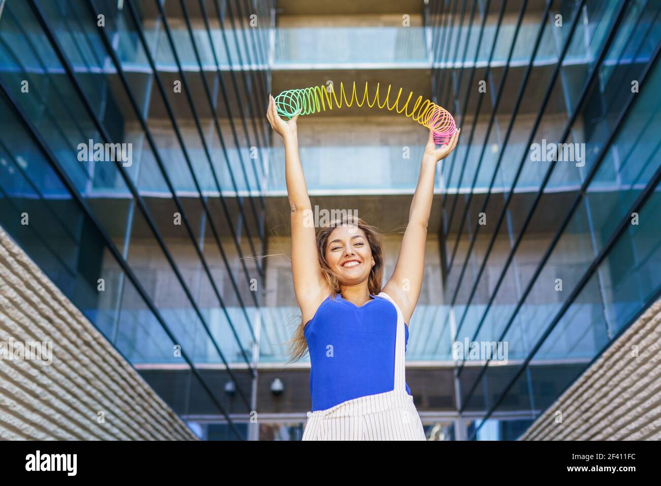 Girl playing with a colorful spring toy in urban background. Girl ...
