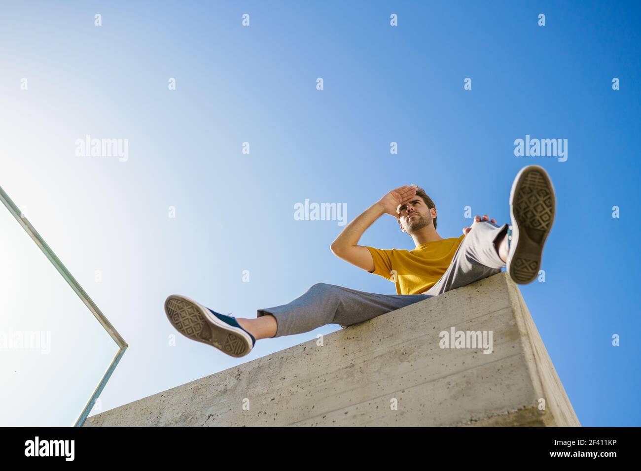 Young man sitting on a ledge looking around. Man sitting on a ledge ...