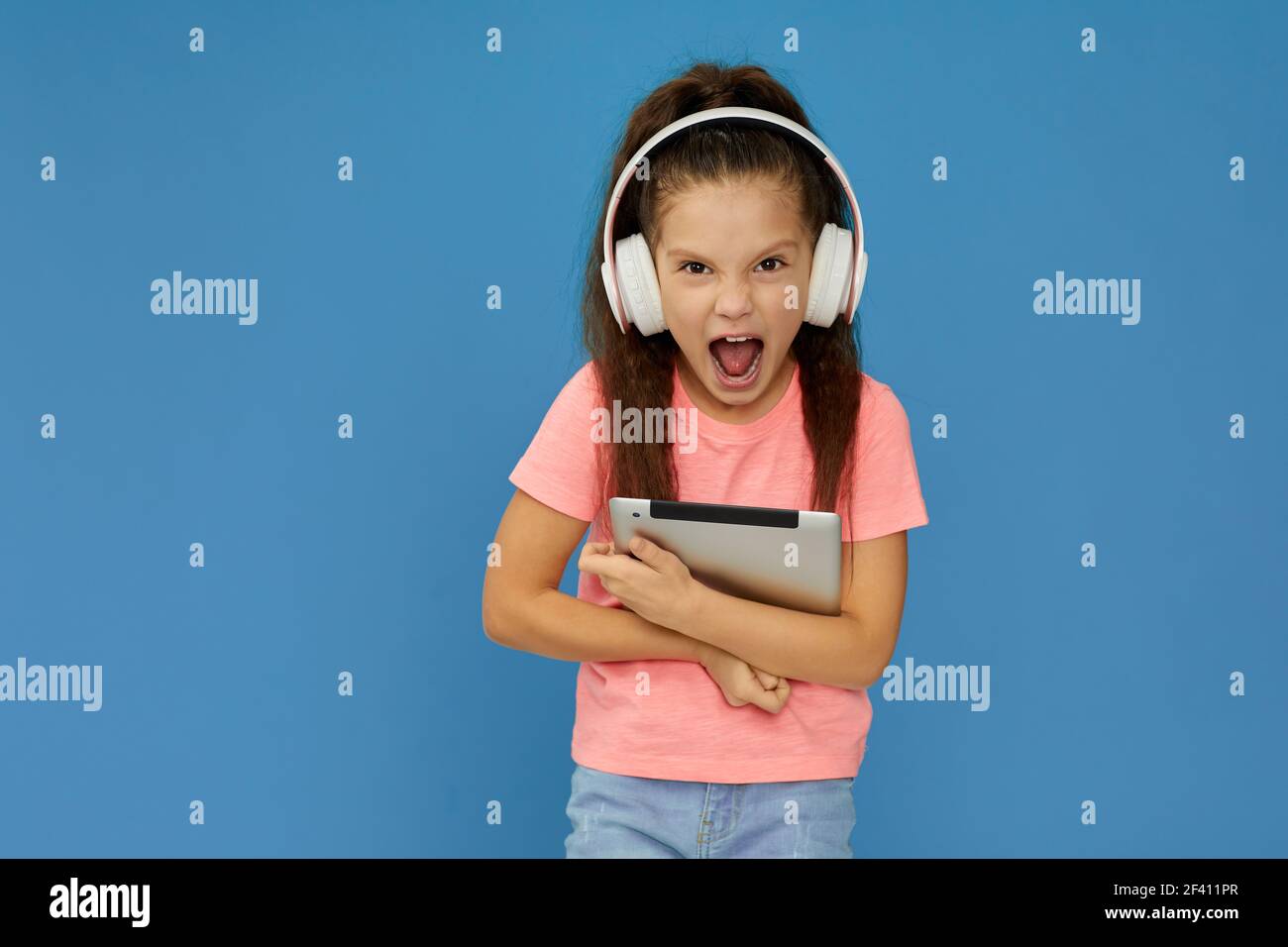 child girl in white headphones holding tablet and screaming Stock Photo ...