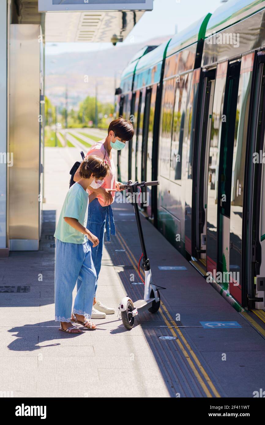 Mother and daughter riding on a train with an electronic scooter ...