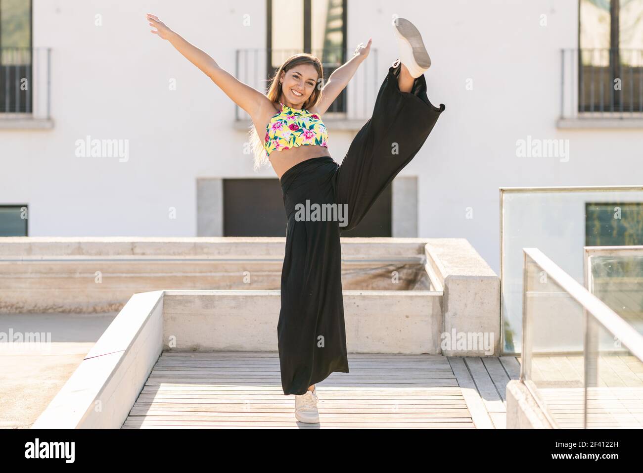 Funny young girl raising arms and leg outdoors. Pretty young girl ...