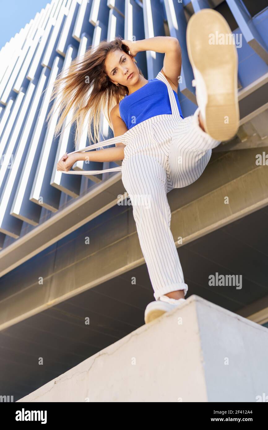 View from below of young girl throwing her foot in the air in urban ...