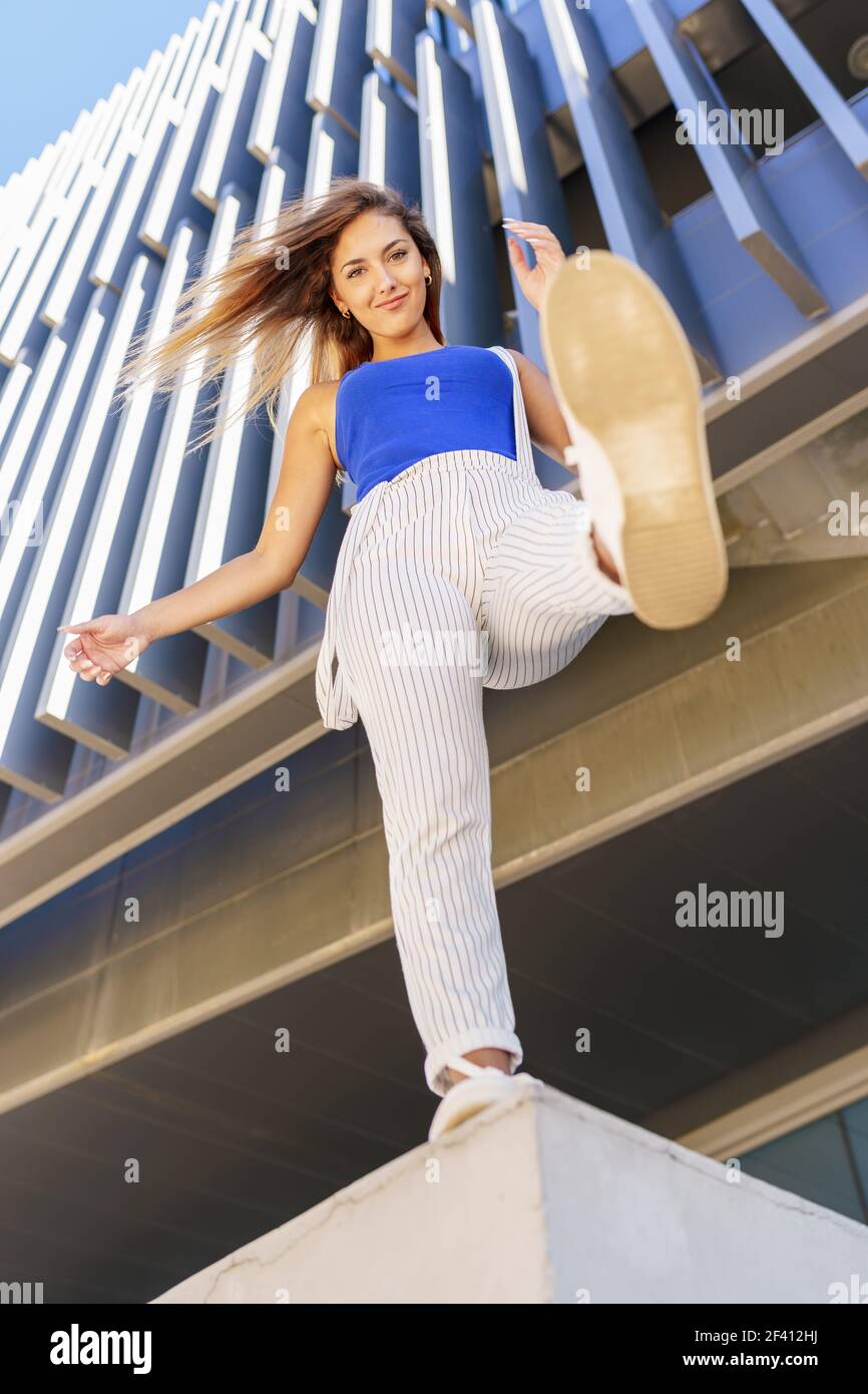 View from below of young girl throwing her foot in the air in urban ...