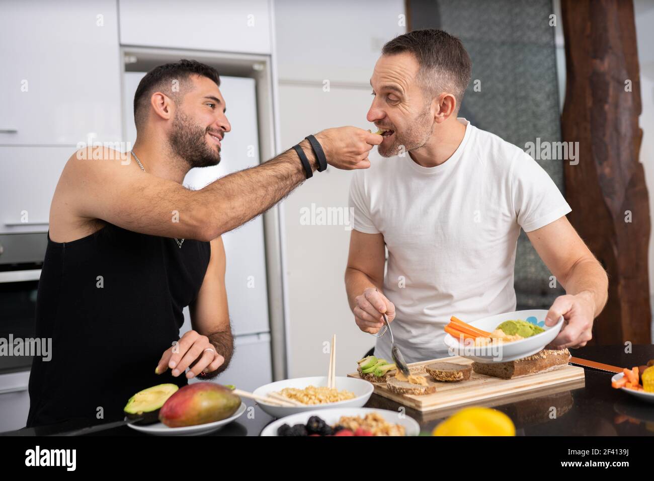 Gay couple cooking healthy vegan food together at home. Homosexual ...