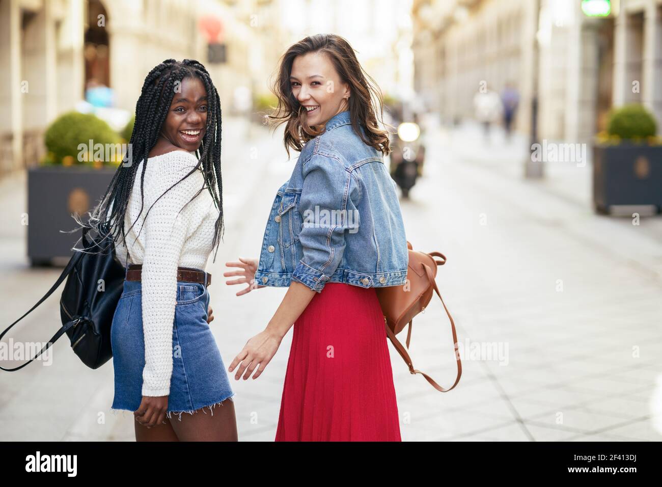 Two friends having fun together on the street. Multiethnic women.. Two female friends having fun ...