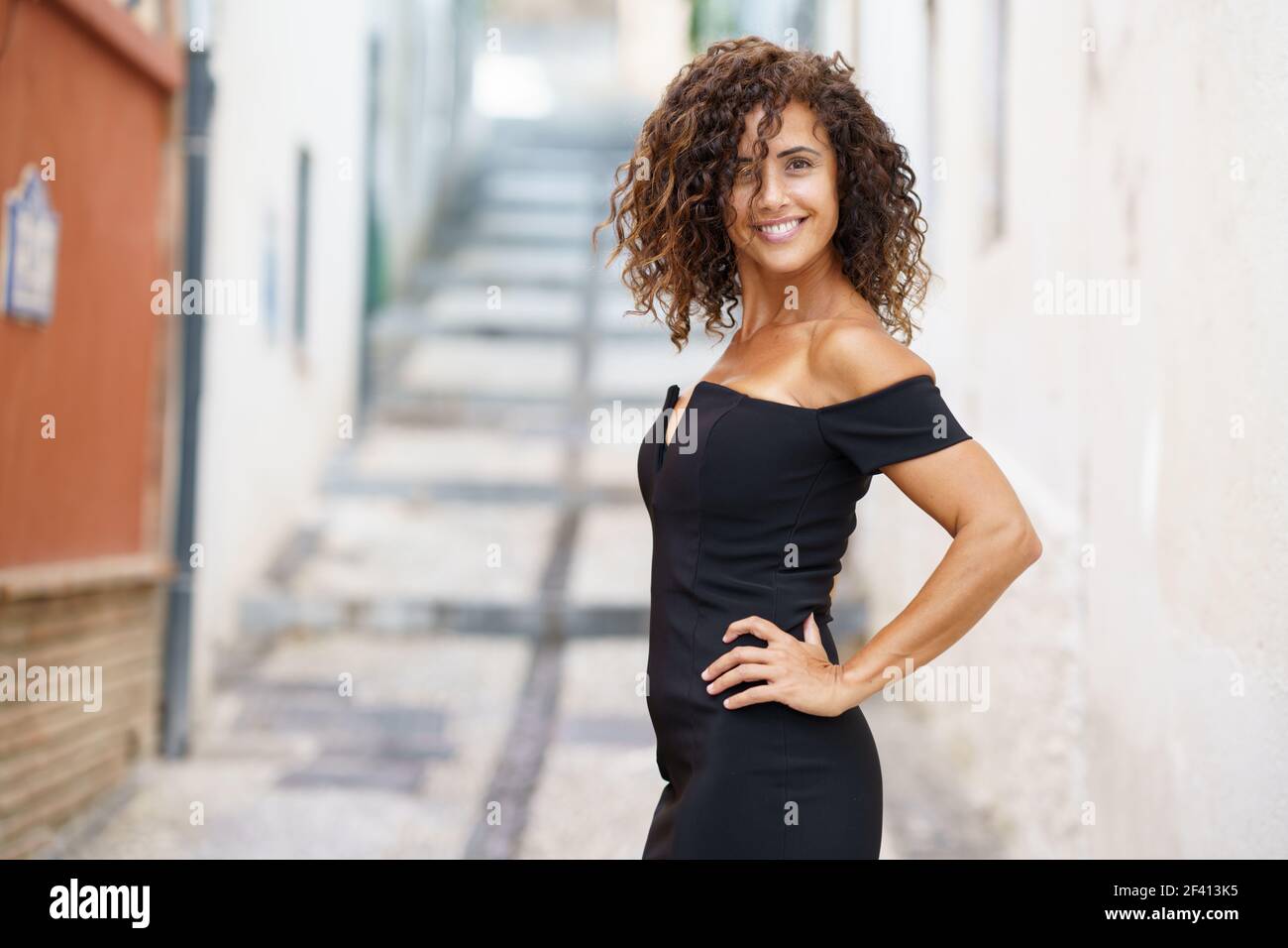 Beautiful brunette middle-aged woman in her 40s wearing dress outdoors ...