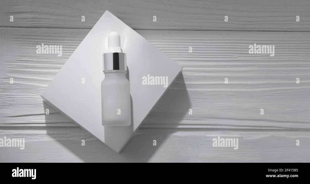 Top view of pipette bottle on white box on wooden table with copy space ...