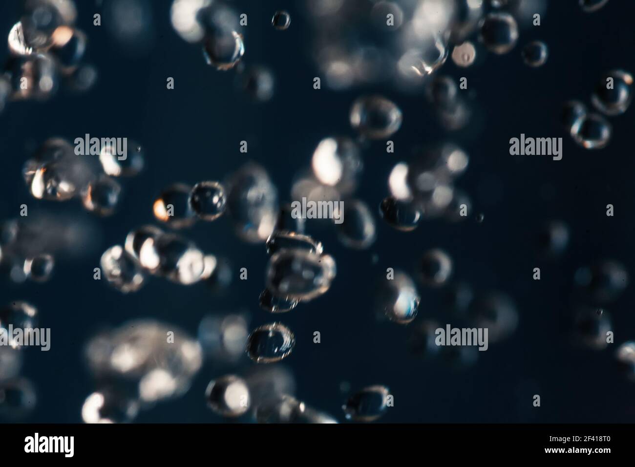 Small water drops frozen in an air on dark blue background. Small water ...