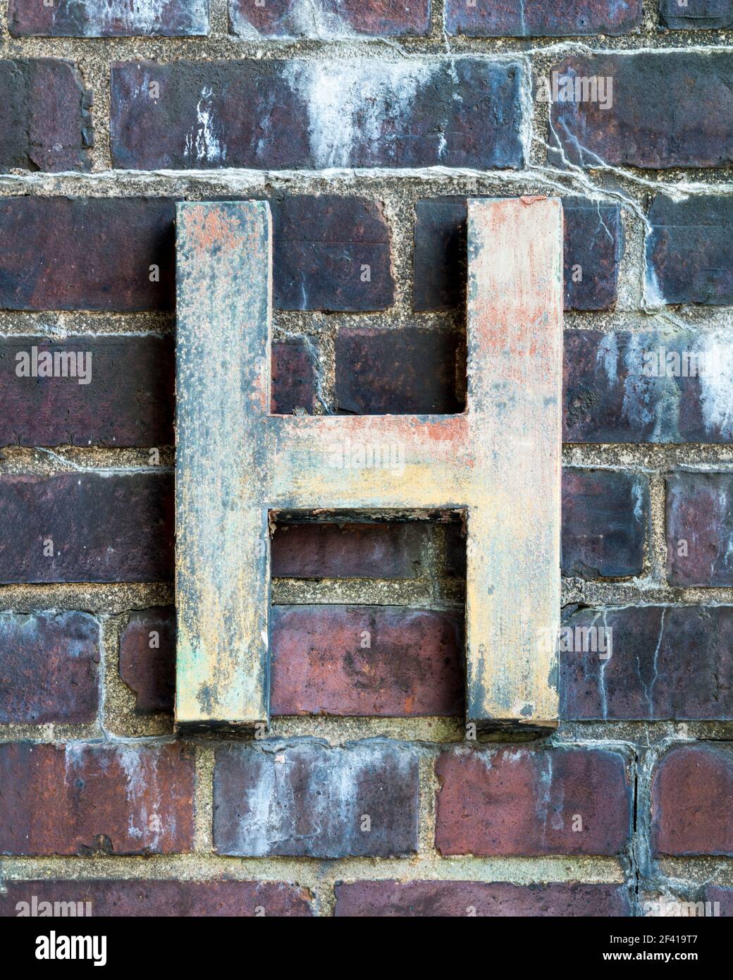 Weathered metal letter H in front of a brick wall Stock Photo - Alamy