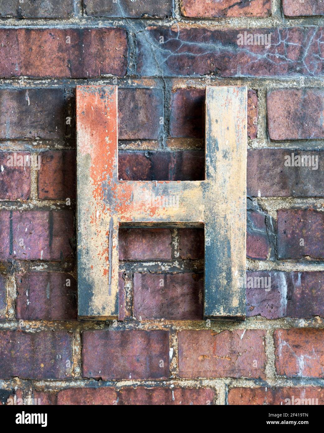 Weathered metal letter H in front of a brick wall Stock Photo - Alamy