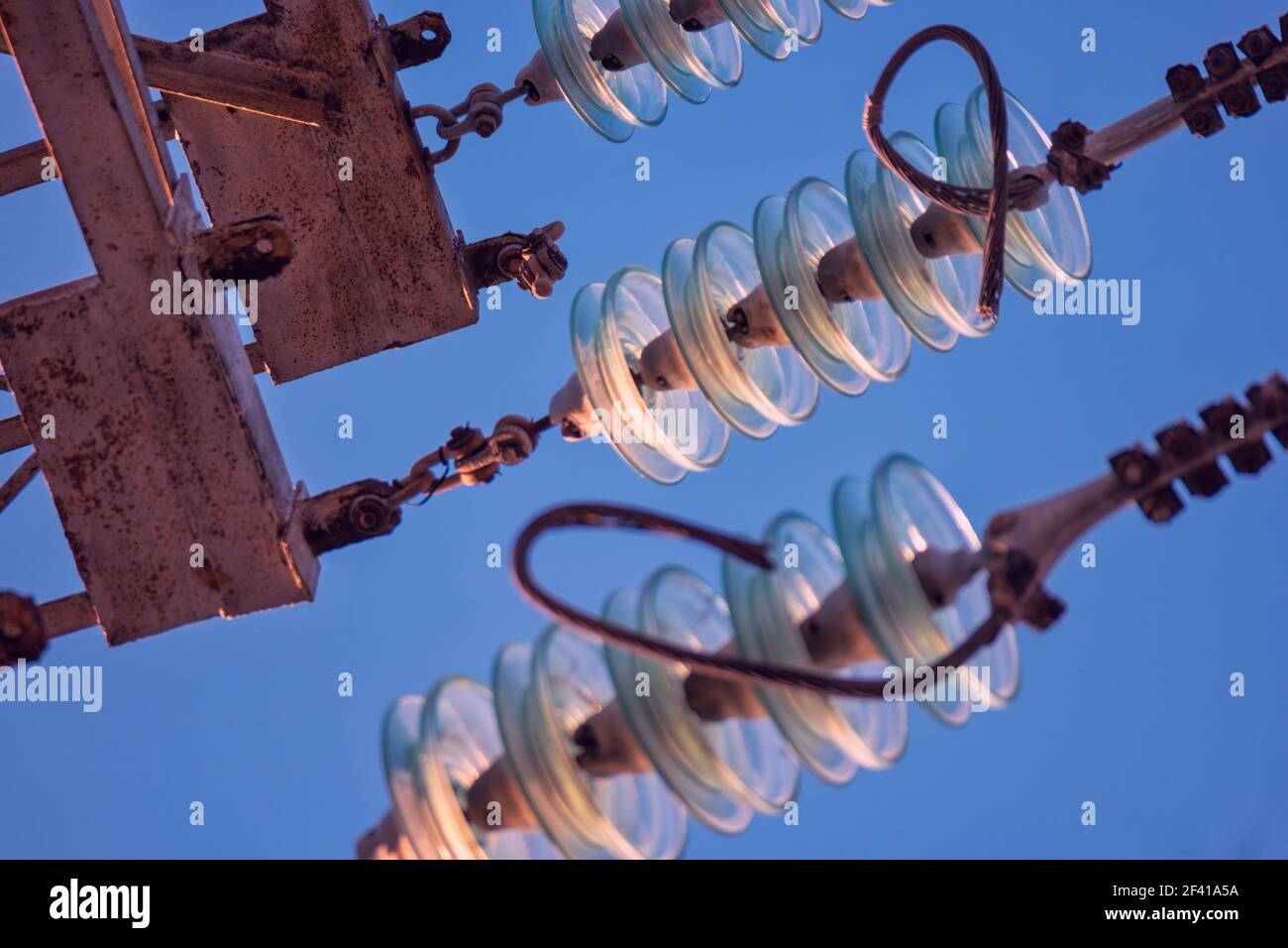 Close up of high voltage insulators at power-tower looking upwards from ...